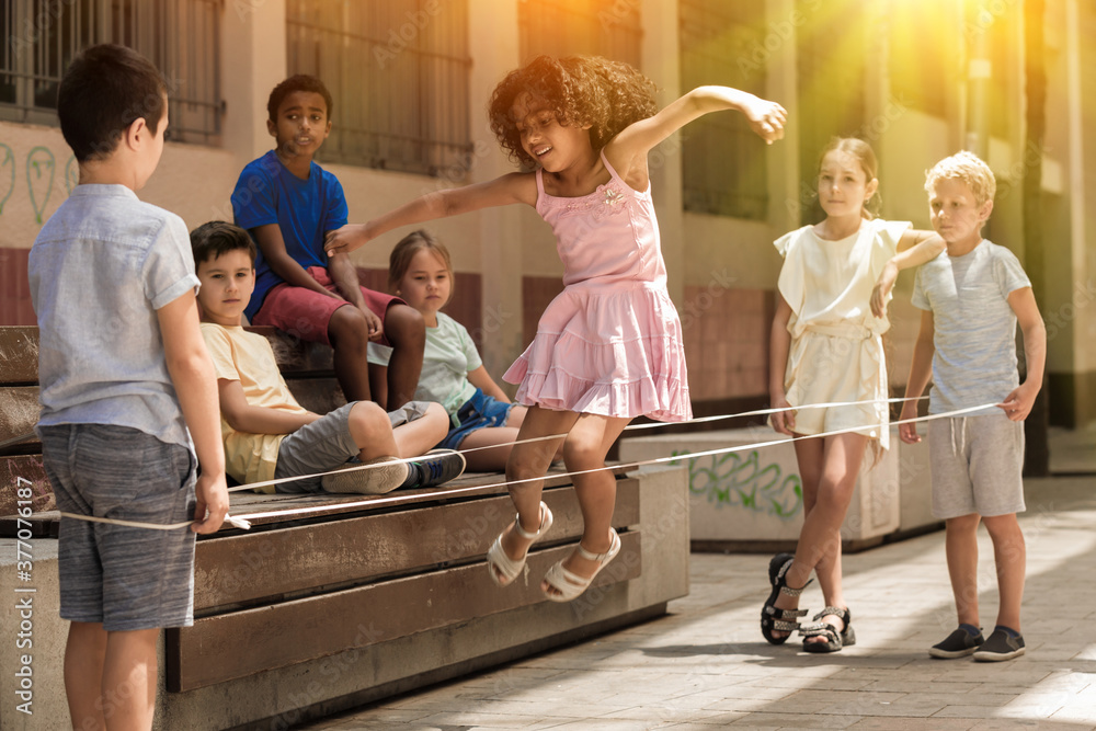Happy peruvian little girl jumping game by rubber band with european ...