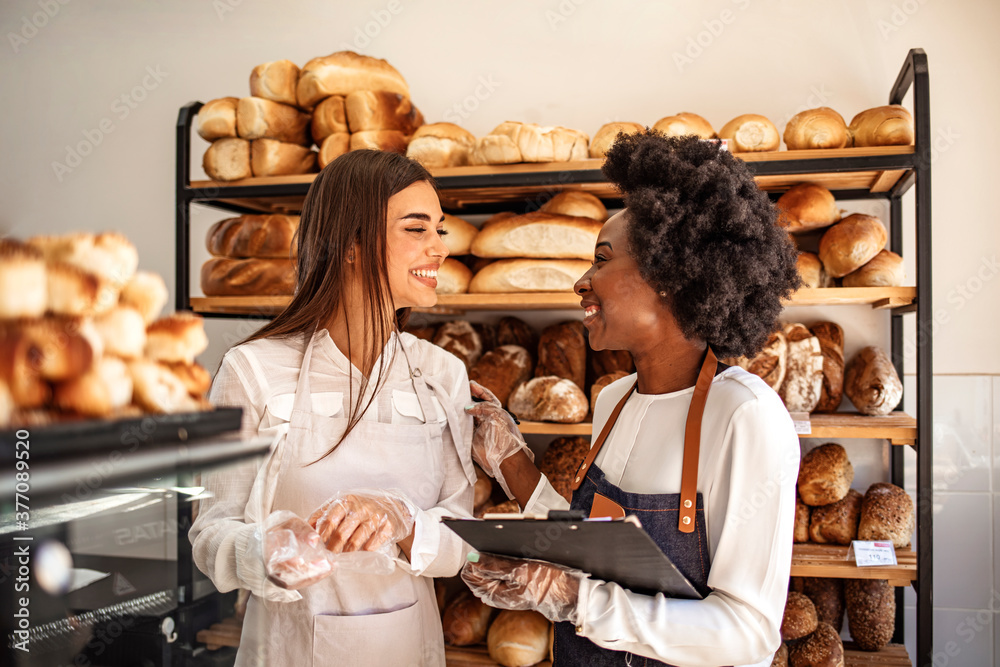 Business owner talking to worker at a bakery. Female business owner ...
