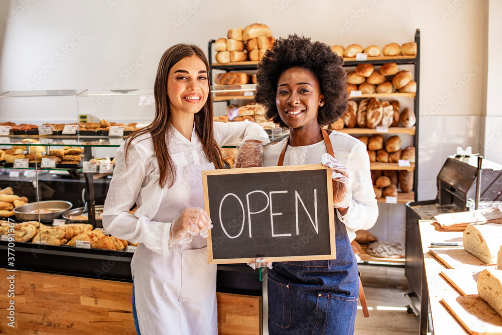 Young business women holding an open sign. Bakery shop female owner ...