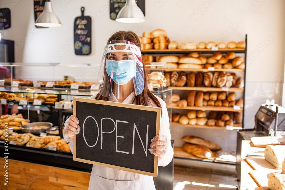 Owner of bakery shop smiling behing her mask. She is following ...