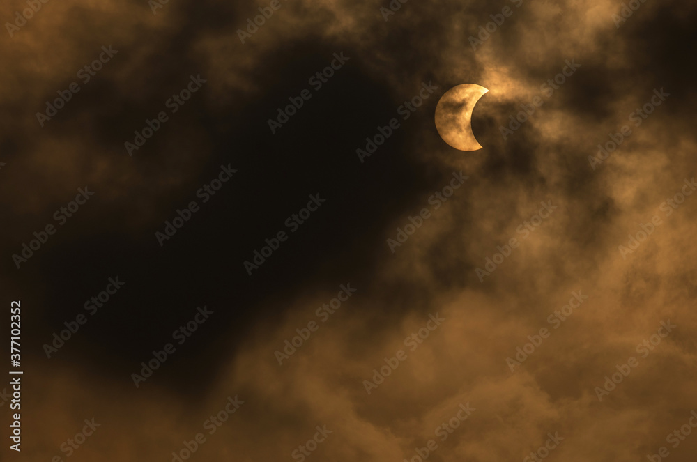 The Moon covering the Sun in a partial eclipse with dramatic cloud ...