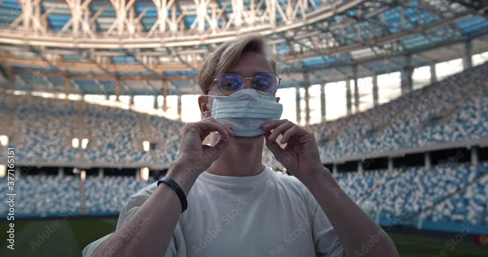 Football or soccer fan wearing medical protection mask on stadium ...