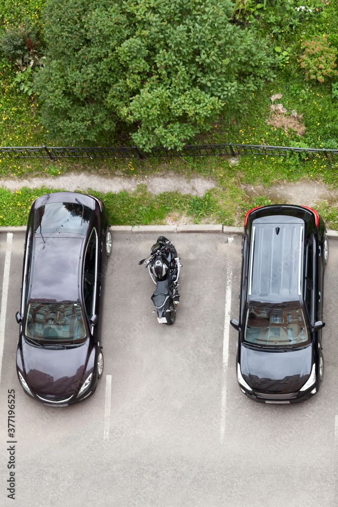 Motorcycle is parked on vehicle parking space between two passenger ...