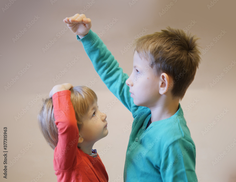 Foto de Happy children measuring to determine who is bigger, power ...