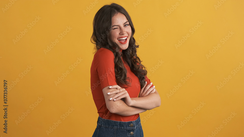 Attractive smiling girl in red top with hands crossed happily winking ...
