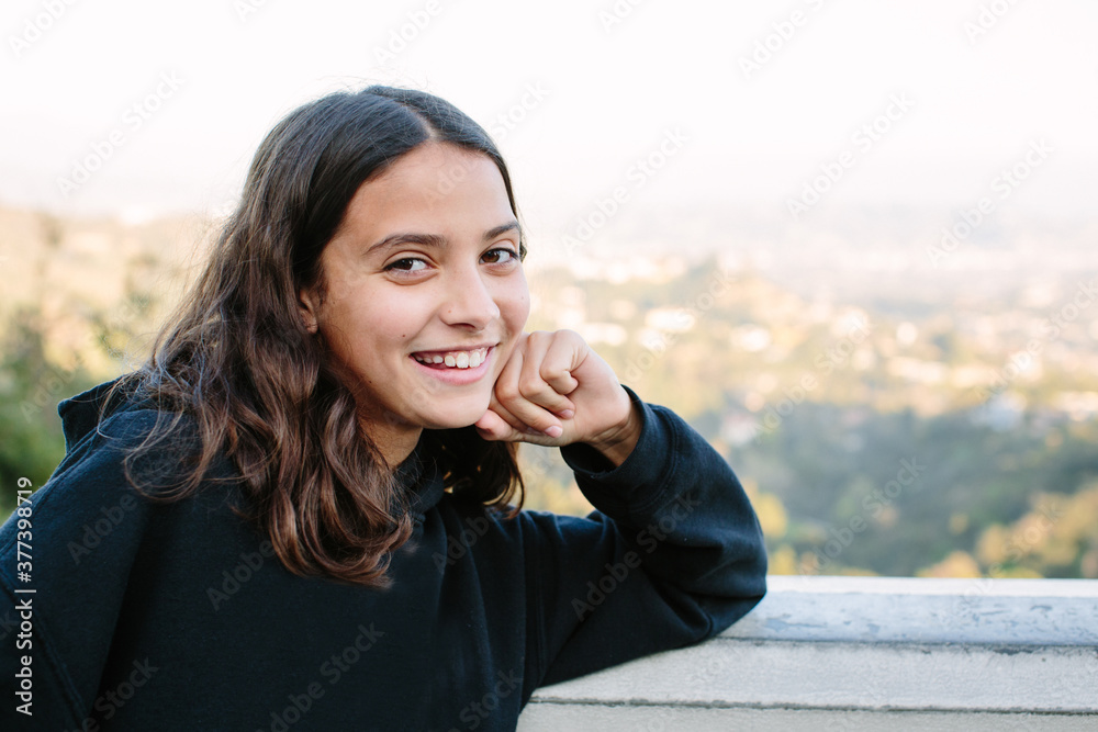 Twelve year old girl smiles for a cheesy portrait at a scenic overlook ...
