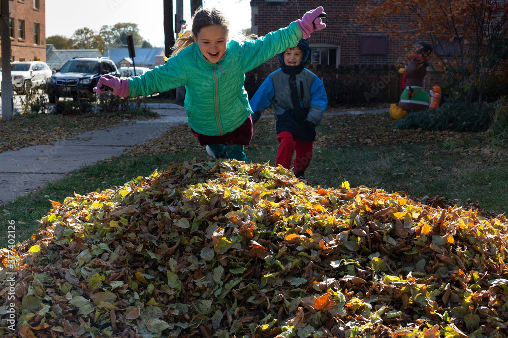 Happy kids jumping into a pile of leaves on a cold fall day Stock Photo ...