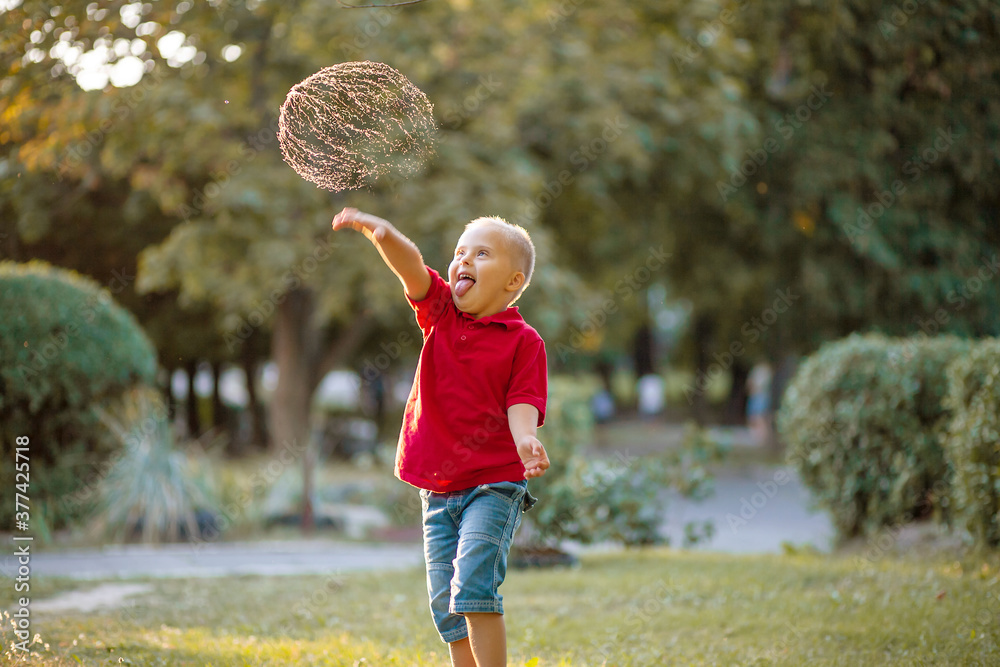 Little cute boy with Down Syndrome plays with huge soap bubbles in the ...