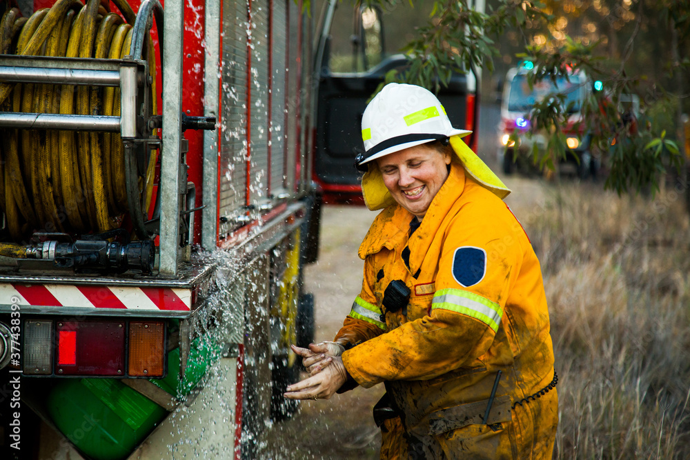 Firefighter laughing and washing her hands besides fire truck Stock ...