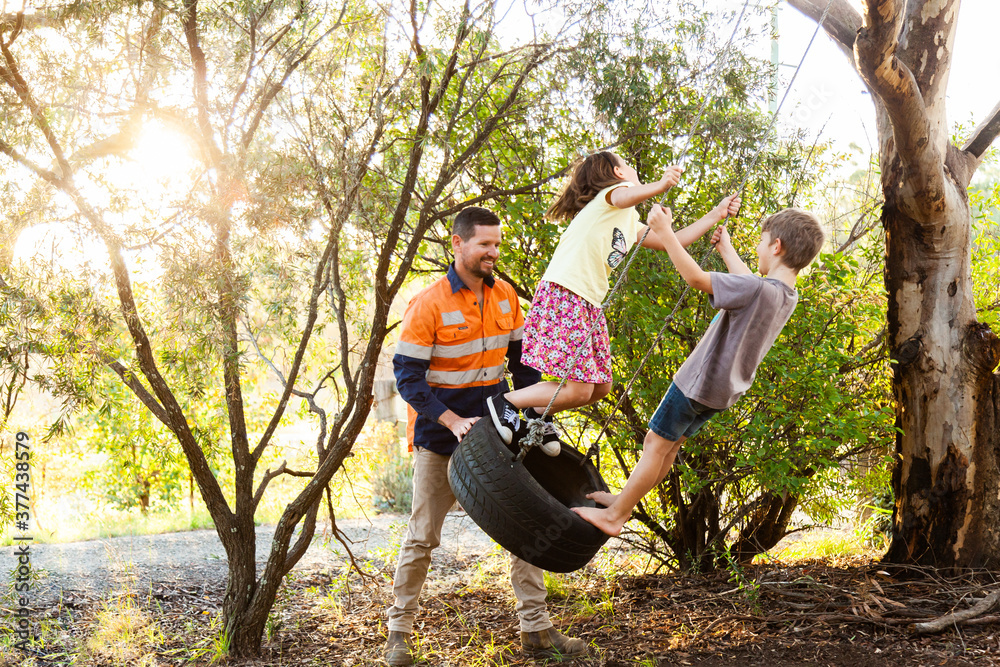 Dad pushing children on tyre swing boy and girl Stock Photo | Adobe Stock