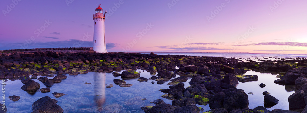 A lighthouse reflected in rock pools against a purple dawn sky Stock ...