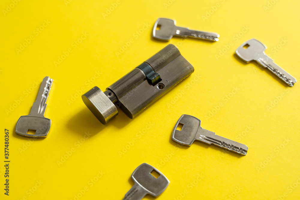 A door lock cylinder core with keys on the yellow background. The ...