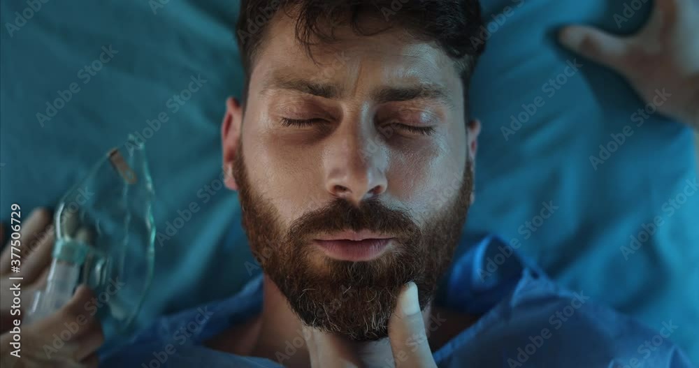 Close up of medics hands putting on ill bearded man oxygen inhalation ...