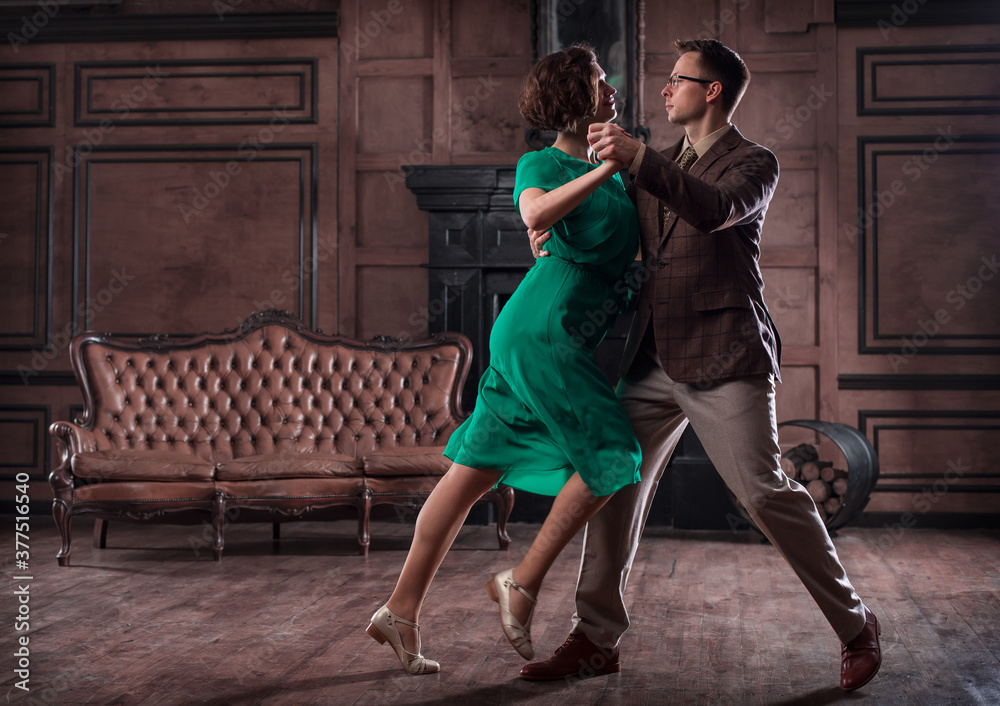 Foto de a young couple dancing in a retro hall in front of a fireplace ...