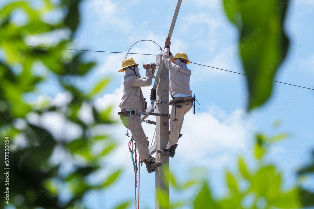 Foto de Electrical experts are on the power poles to install steel ...