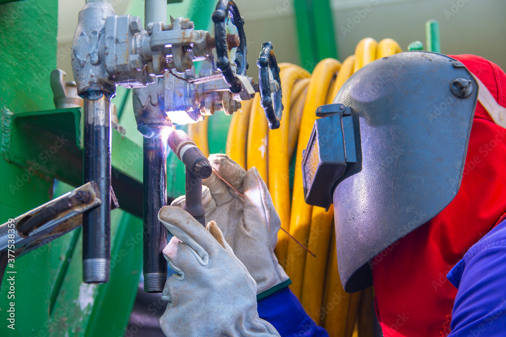 The welder is welding the steel pipe to the valve with Tungsten Inert ...