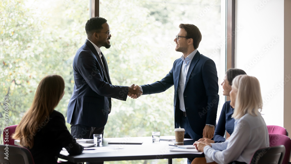 Happy multiracial male business partners handshake close deal or make ...
