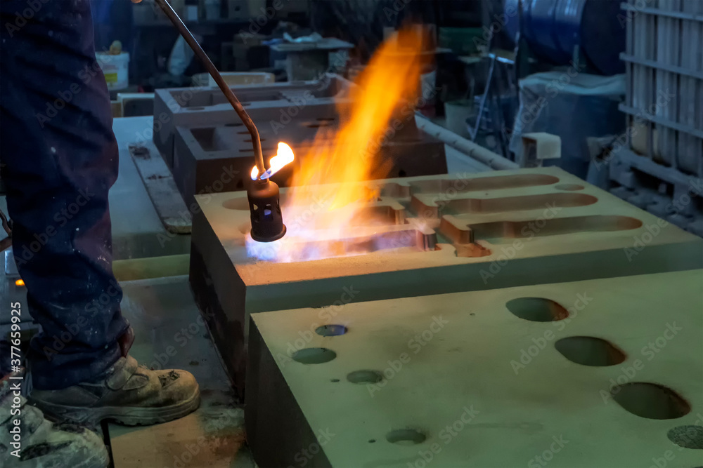 The worker is preheating to mold for casting. Sand casting, also known ...