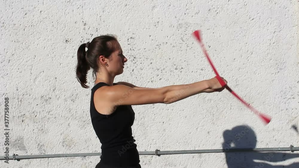 A young female, a circus performer, spinning Poi on the street ...