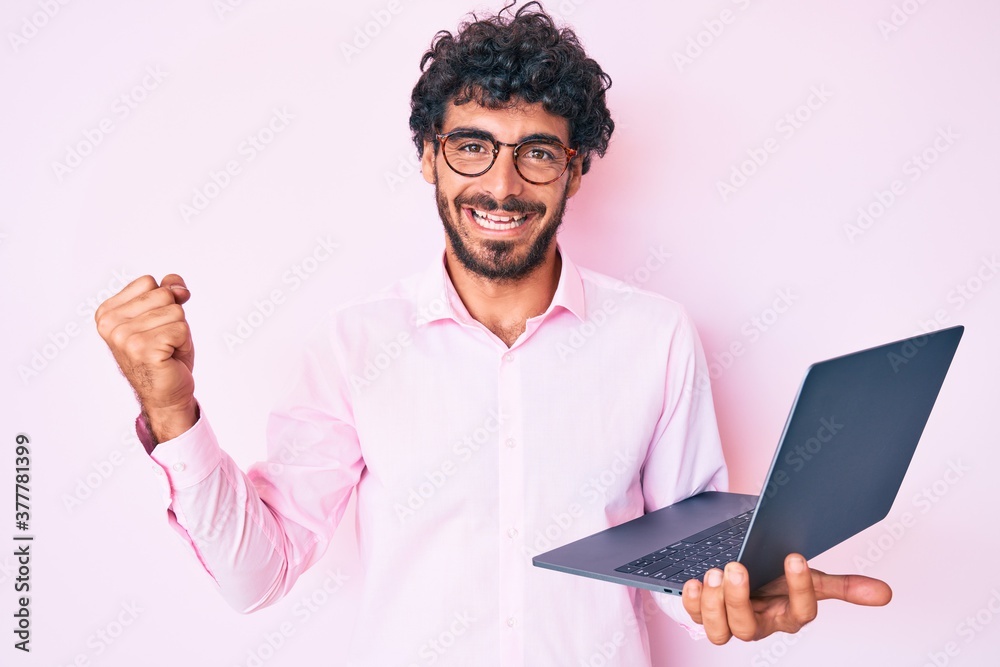 Handsome young man with curly hair and bear working using computer ...