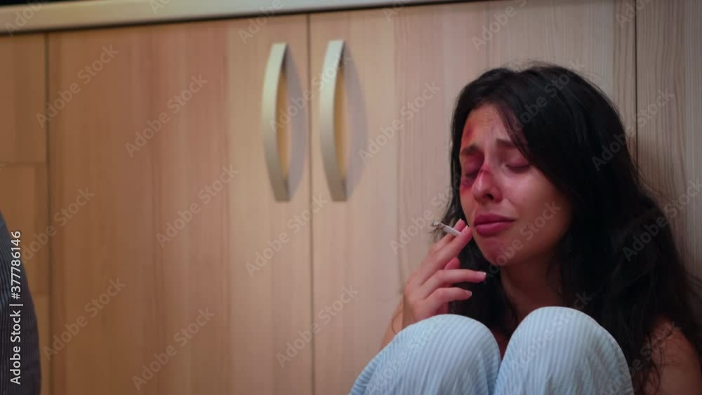 Traumatised wife smoking and crying sitting on the floor. Abused ...