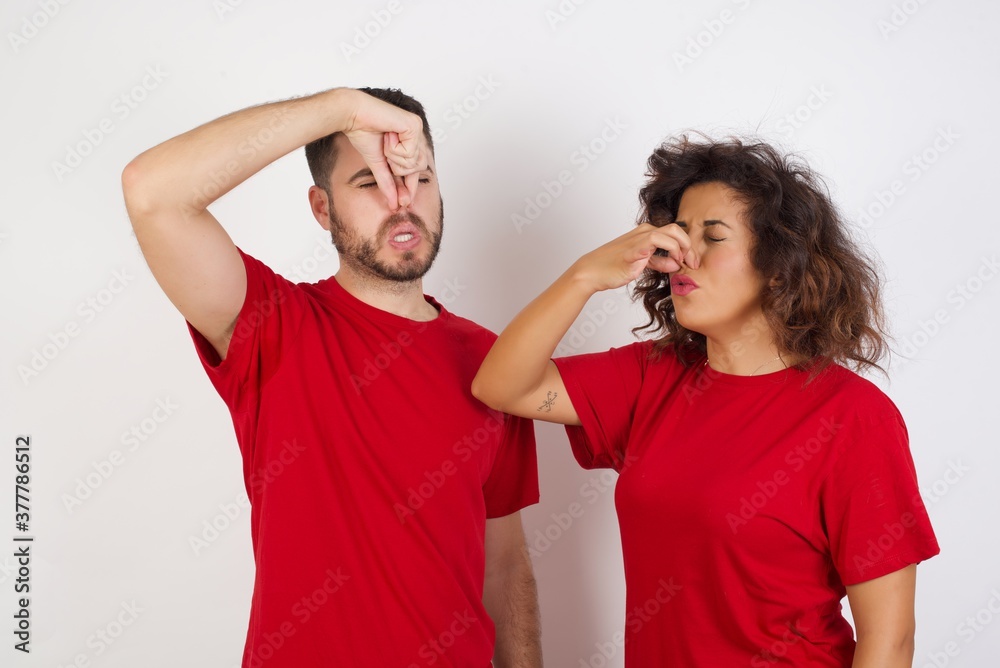 Young beautiful couple wearing red t-shirt on white background smelling ...