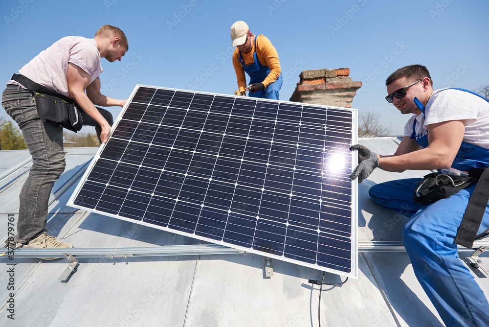 Male team workers installing solar photovoltaic panel system. Three ...