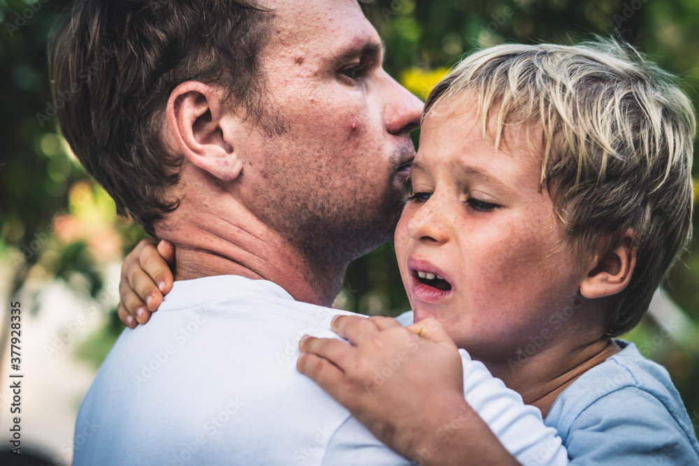Closeup Sad young blond boy crying on father hands in nature park ...