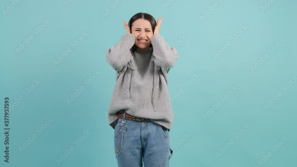 Confused woman holding hands on ears and shouts over turquoise studio ...