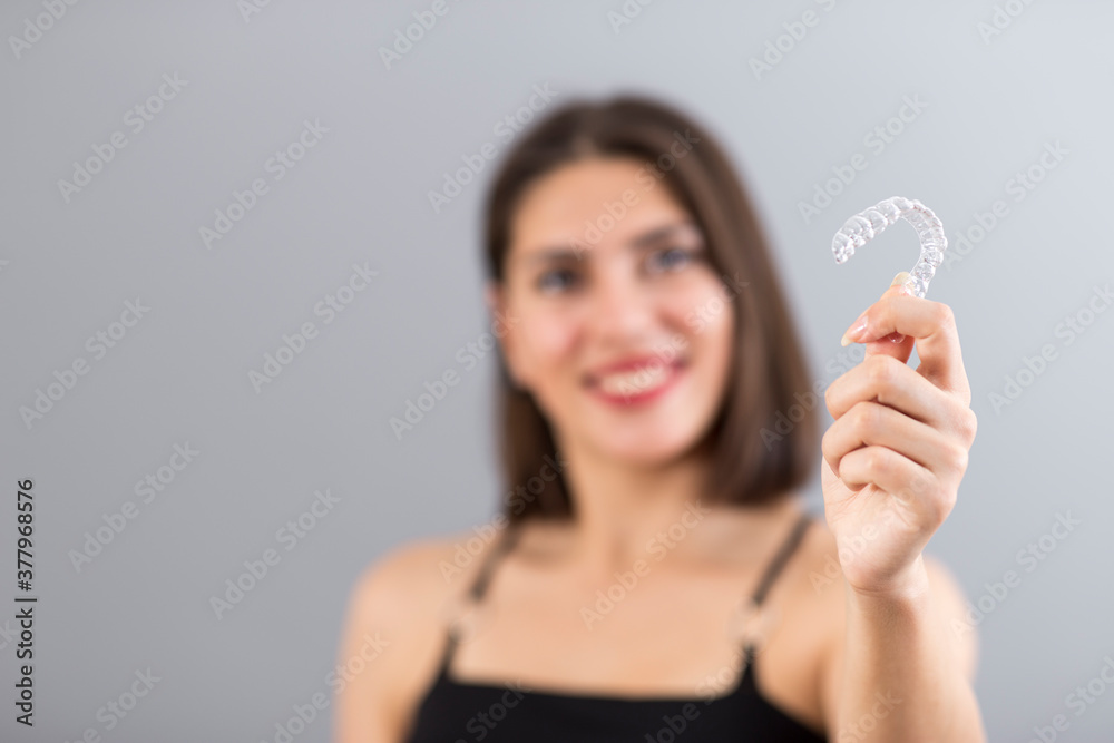 Beautiful smiling Turkish woman is holding an invisalign bracer ...