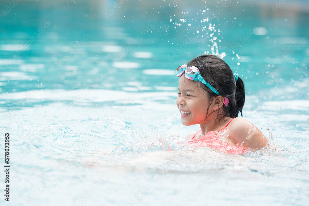 smiling child wearing swimming glasses in swimming pool. little girl ...