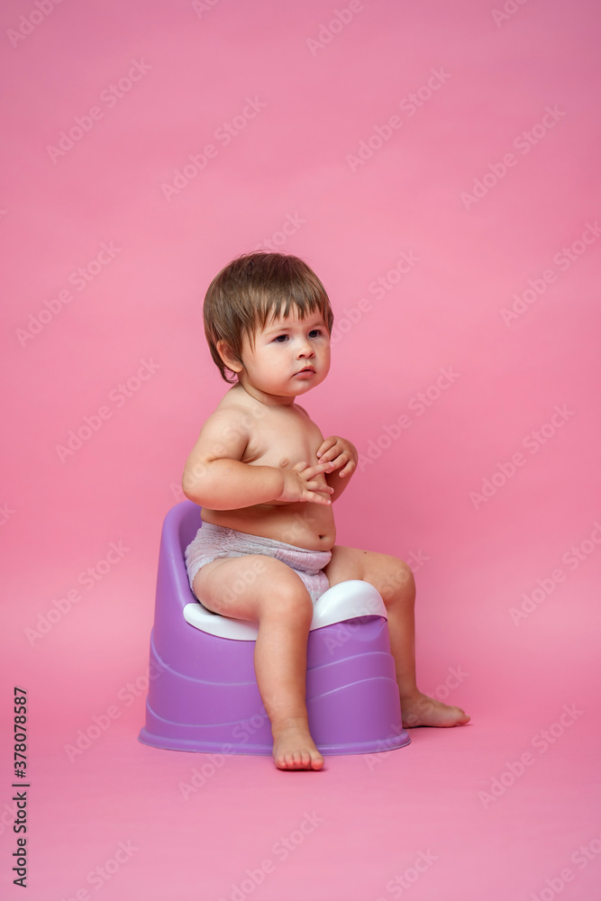 Cute baby in a diaper sitting on a potty. Toilet and potty training ...