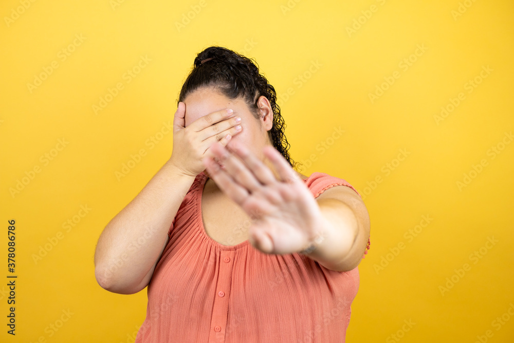 Young beautiful woman with curly hair over isolated yellow background ...