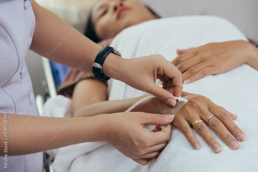 Nurse applying an IV drip to an Asian female patient hand on bed ... Nurse applying an IV drip to an Asian female patient hand on bed ...