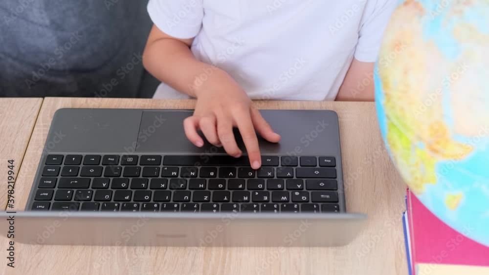 kid, schoolboy, slowly typing text on a black laptop keyboard with his ...