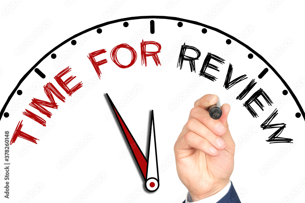 Hand writing TIME FOR REVIEW on drawn clock with marker on transparent ...