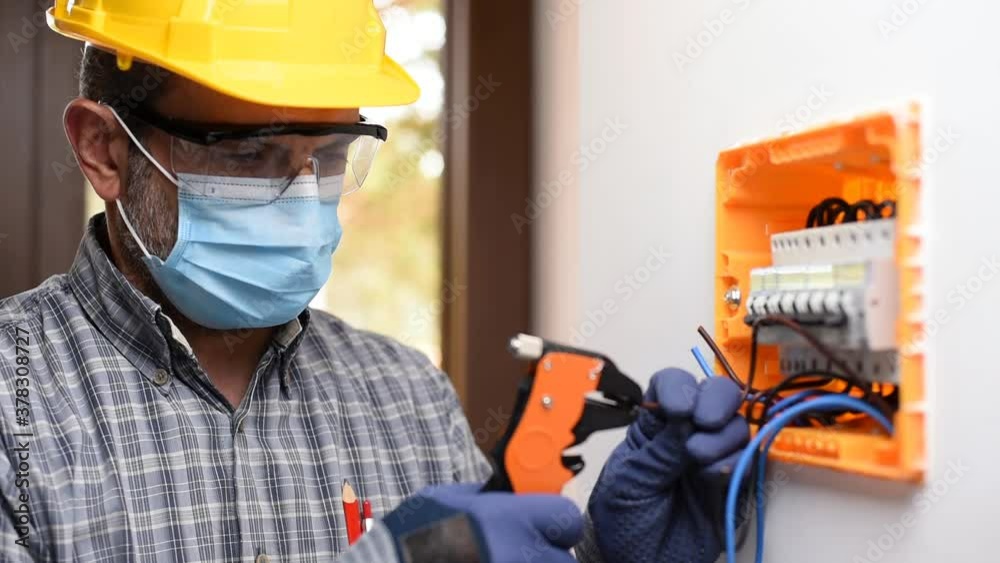 Vídeo do Stock: Electrician at work on an electrical panel protected by ...