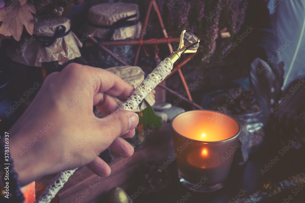 Woman hand is holding magic wand performing a pagan witch ritual. Toned ...