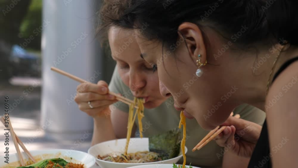 Two girls eating their delicious traditional Japanese ramen soups ...