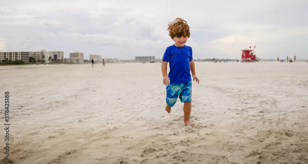 Boy playing on the beach at siesta Key florida with the snd and birds ...