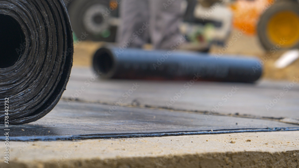 MACRO Detailed shot of a bitumen roll as worker burns a layer of ...