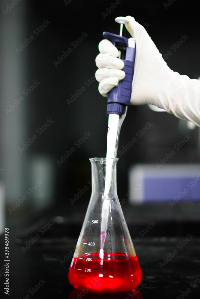 aspirating a red chemical on a glass conical flask with a automated ...