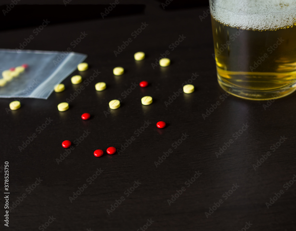Ecstasy Pills with blur image of beer in glass on black background ...