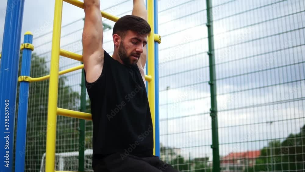 Athletic man training core muscles with leg lift on vertical ladder ...