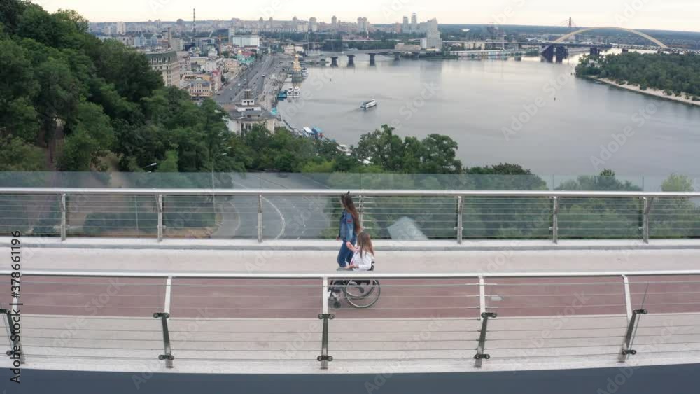 Aerial shot of disabled woman riding wheelchair holding hands and ...