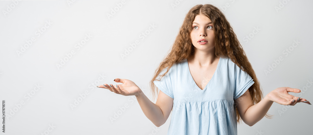 Confused girl spreads hands sideways, feels doubt while makes choice ...