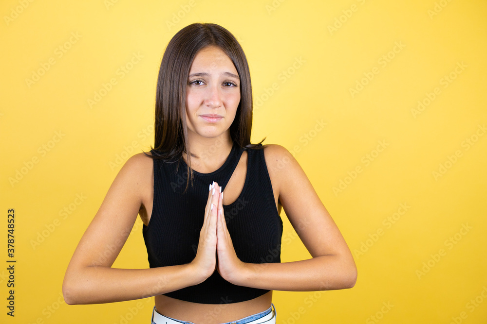 Beautiful young girl kid over isolated yellow background begging and ...