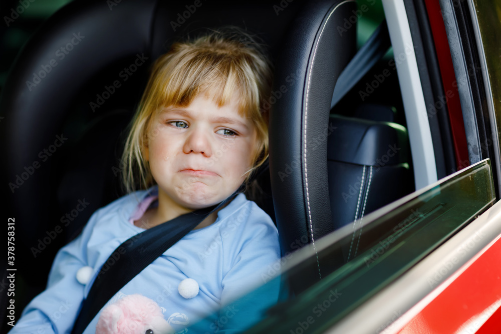 Sad upset little kid girl sitting in car in traffic jam during going ...