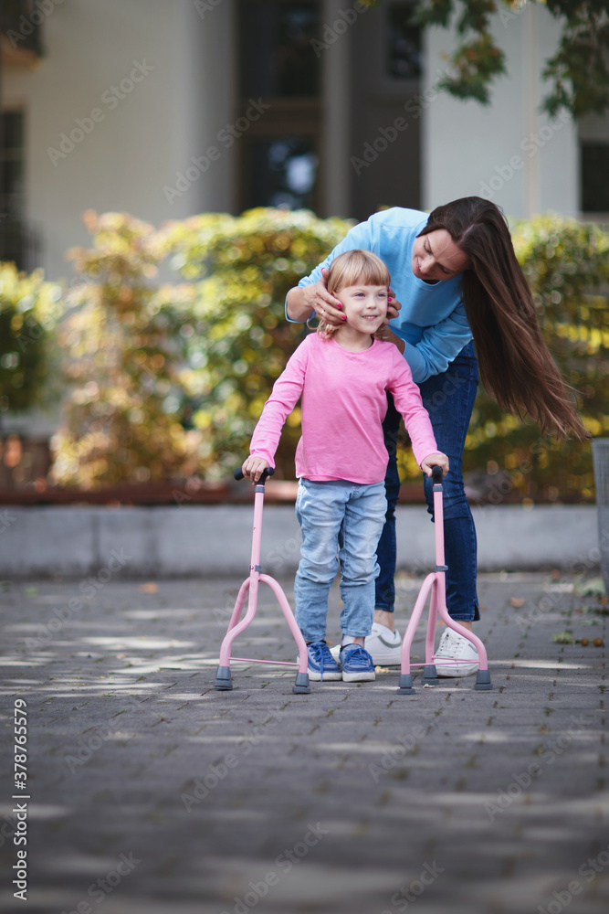 Smiling happy little girl walking on crutches, mother helps to go Stock ...