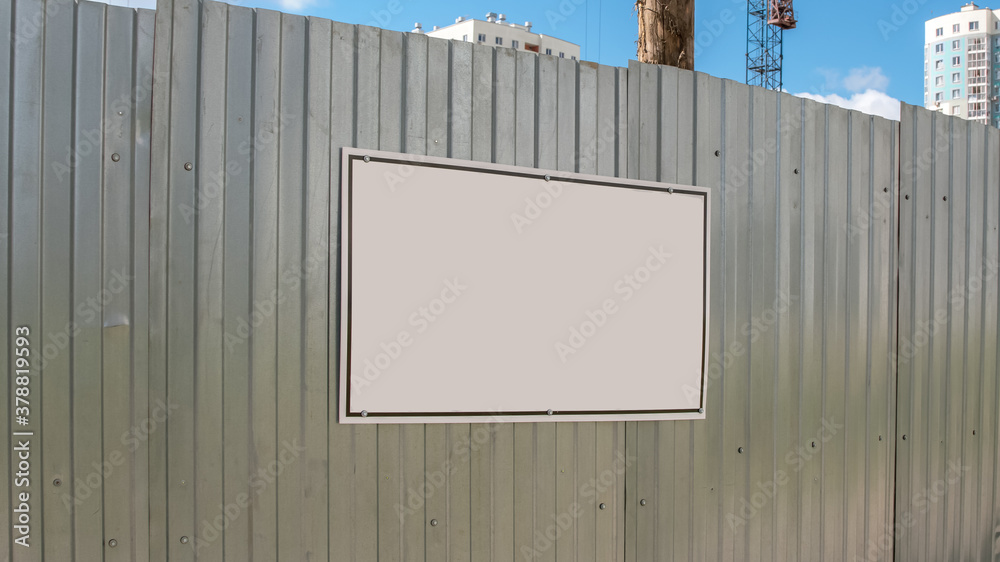 empty information board with mockup on steel fence of construction site ...